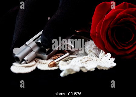 Red Rose with handgun, bullets and hand in black glove on black ...
