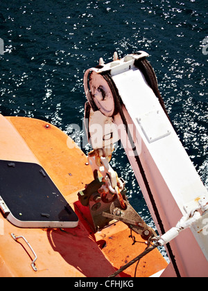 Orange life boat hanging on a crane on a deck of sailing ocean ship ...