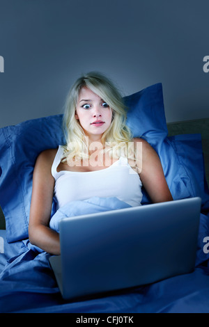 Blonde woman using laptop at night at home very happy and excited doing ...