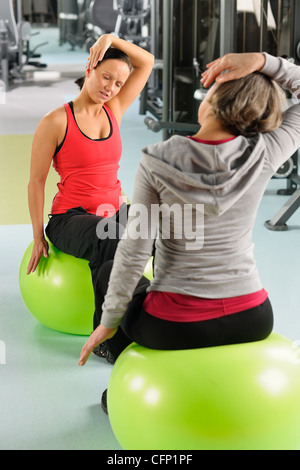 Senior woman with trainer stretching fitness ball Stock Photo - Alamy