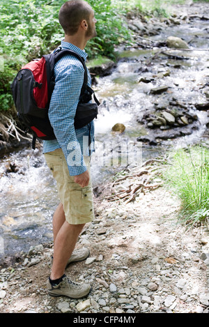 Man hiking along stream in woods Stock Photo - Alamy