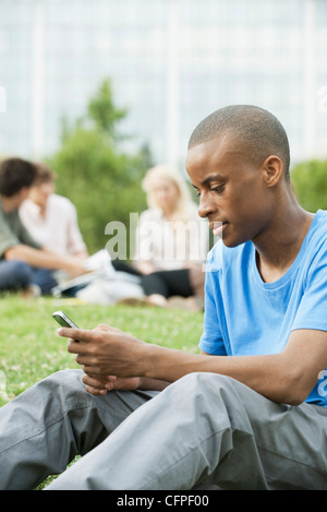 Young man text messaging on mobile phone while using laptop Stock Photo ...