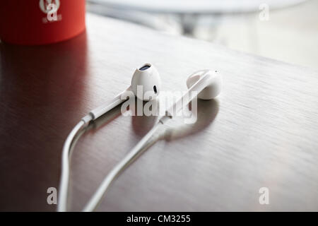 Inside a coffee shop, a newly released pair of Apple EarPods sit on a ...