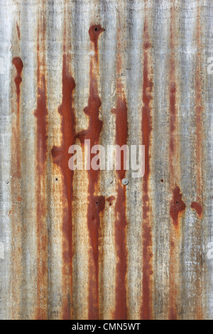Weathered corrugated metal wall with rust and aged paint creating an ...