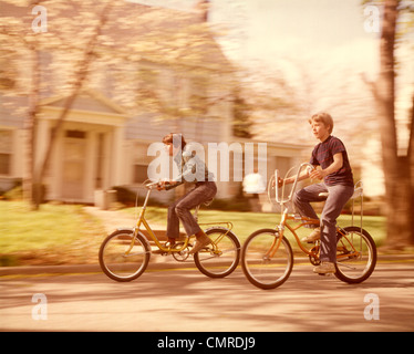 1970s TWO BOYS RIDING BIKES DOWN SUBURBAN NEIGHBORHOOD SIDEWALK Stock ...