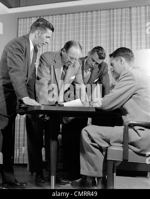 1950s FOUR MEN IN AN EXECUTIVE OFFICE DISCUSSING A DOCUMENT THE BOSS IS ...