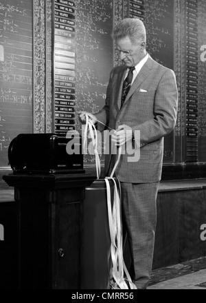 1950s 1960s STOCKBROKER READING TICKER TAPE IN FRONT OF STOCK EXCHANGE ...