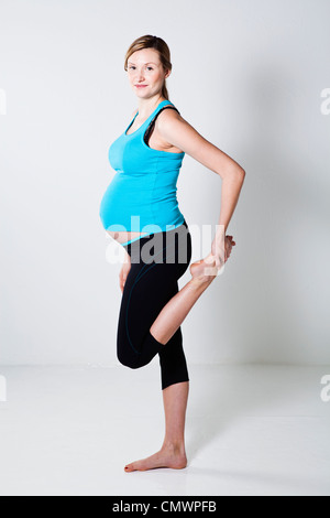 Pregnant woman performing a leg stretching exercise for the hamstring ...