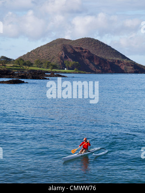 Man paddling a one-person outrigger canoe off the island of Maui ...