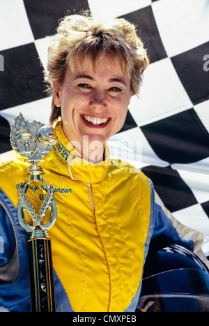 Blond female racing car driver poses with checkered flag and winning ...