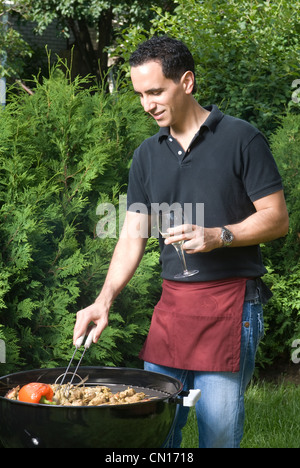 Man BBQing holding a glass of wine, Laval, Quebec Stock Photo: 47355980 ...