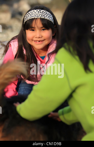 Portrait of young First Nation girls hugging a totem pole, Vancouver ...