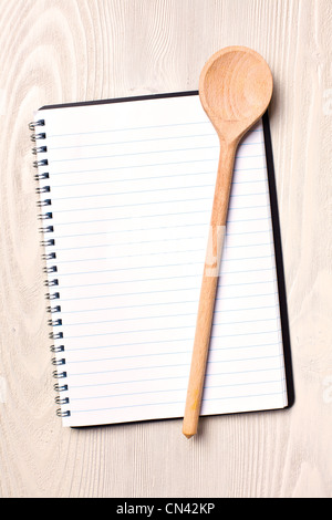 Wooden spoon and book on a wooden board with a checkered tablecloth ...