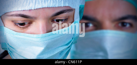 Closeup portrait of two surgeons during a surgery. Blue cast and ...