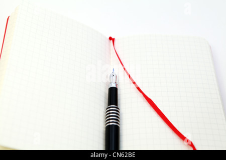 Fountain pen on a notebook. Black ink splash. Wooden table. Copy space ...