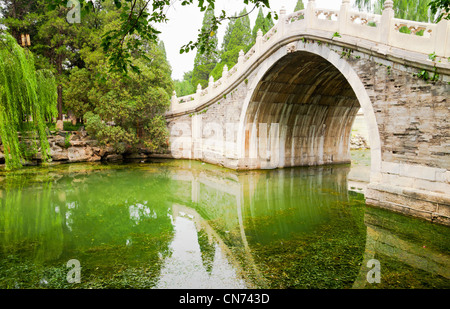 Old style stone Chinese arch bridge in a green garden pond in Beijing ...