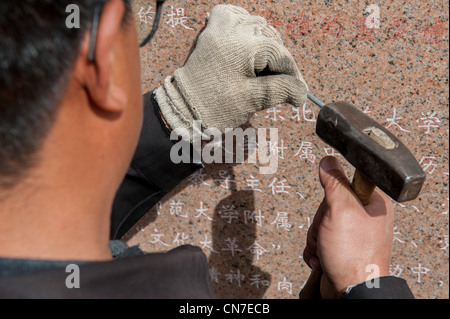 Beijing, Wanan cemetery. Hand of a man engraving a biography of a ...