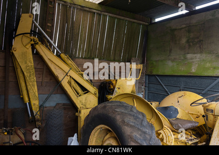 Yellow tractor stored undercover in a smallholding shed during spring ...