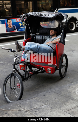 New York City pedicab driver talks with a passenger in the rain while ...