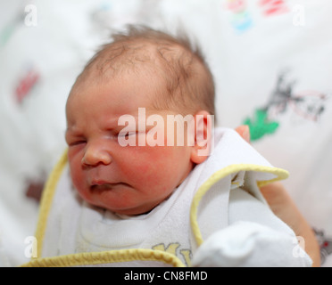 Premature baby. Face a premature baby asleep in a cot wrappped in warm ...