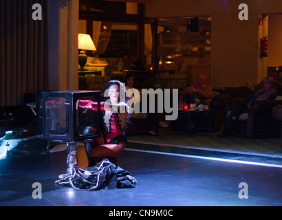Contortionist woman enters-exits small cube, hotel cabaret show. Gran ...