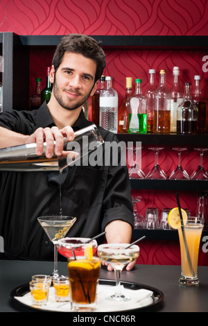 Handsome barman making elegant cocktail in night club on bar counter ...