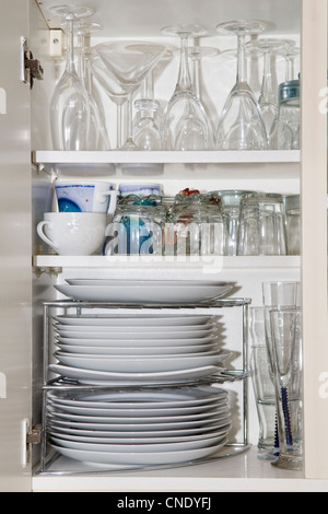 Kitchen cupboard contents showing crockery and glasses Stock Photo - Alamy