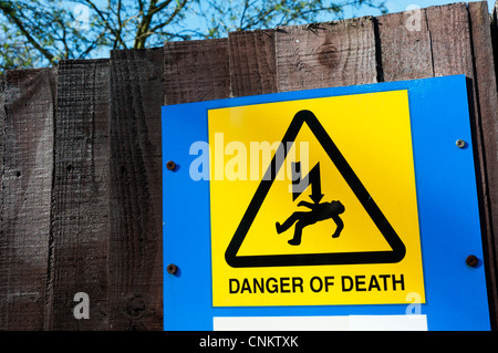 A triangular 'Danger of Death' warning sign on a wooden pole carrying ...