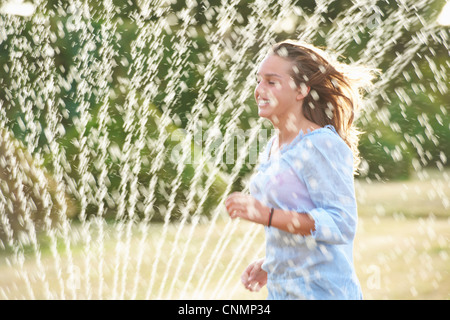 A young woman running through a sprinkler in the grass Stock Photo - Alamy