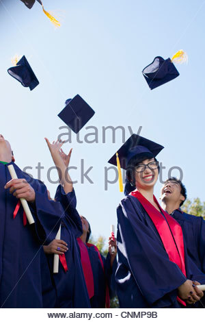 Graduates tossing caps in air, at a high school graduation ceremony ...