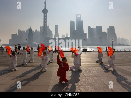 People practicing Taiji with red fans on the Bund, Pudong skyline in ...