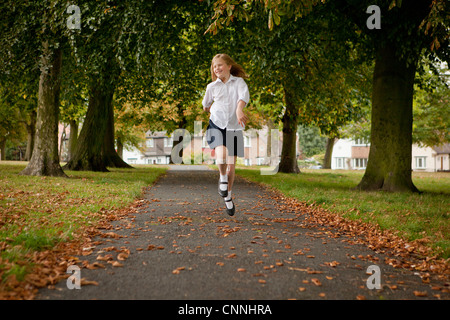 Young female child skipping on a rock path in the spring time. Back is ...