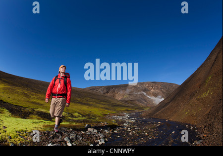 Hiker crossing rocky rural stream Stock Photo - Alamy