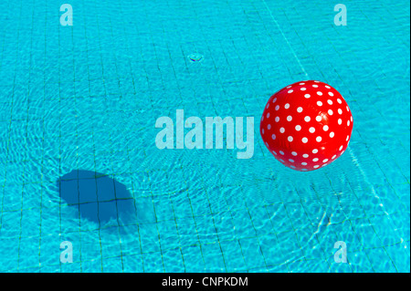 Red ball floating in clear blue swimming pool water, plaything in ...