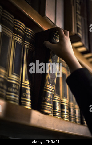 Hand pulling a book from a library shelf Stock Photo - Alamy