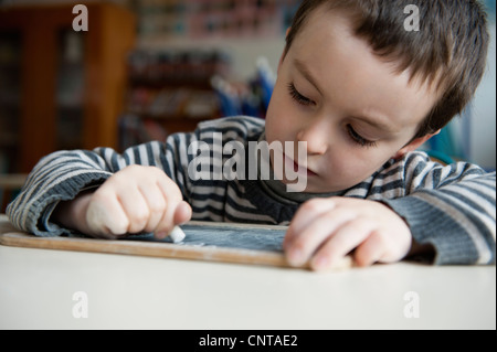Boy writing on chalkboard Stock Photo - Alamy