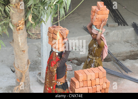Women carrying bricks on her head. She is working on a construction ...