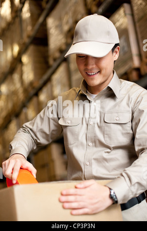 Male Chinese warehouse worker packing a box Stock Photo - Alamy