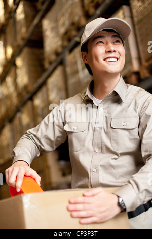 Male Chinese warehouse worker packing a box Stock Photo - Alamy