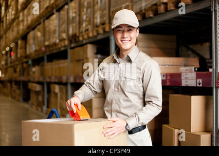 Male Chinese warehouse worker packing a box Stock Photo - Alamy