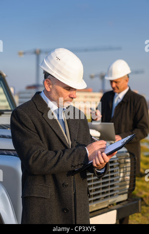 Male architect developers on construction site making notes building ...
