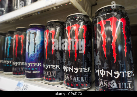 Cans of Monster energy drinks on display on sale on a shelf in a ...