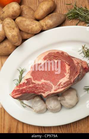 Vertical view of a large uncooked prime rib roast along with garnishes ...