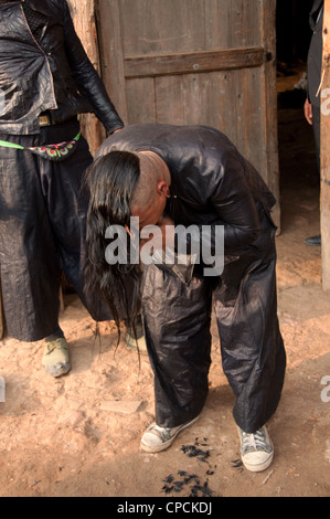 A young Basha Miao (Gun Men) man having his hair shaved by a sickle ...