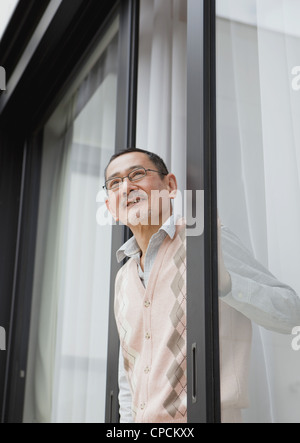 Senior man leaning out of window Stock Photo - Alamy