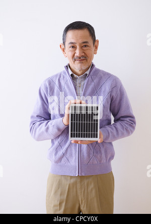 Smiling senior man holding solar house model by grandson in front of ...