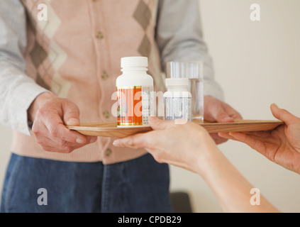 Woman handing over glass of water to man sitting on couch Stock Photo ...