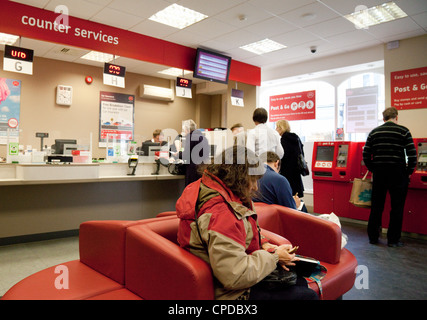 Post Office counter UK; People at the counter inside an English Post ...