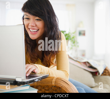 Woman typing on laptop while laughing Stock Photo - Alamy