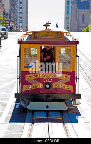 Cable car crossing California Street with Bay Bridge backdrop in San ...